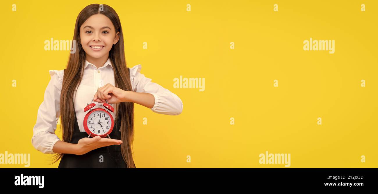cheerful kid in school uniform with alarm clock showing time on yellow ...