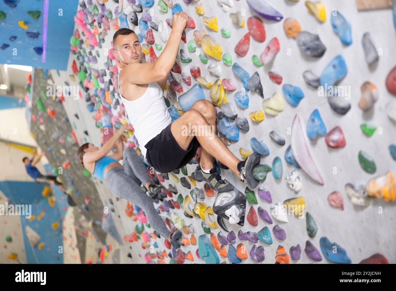 Atlete man grabbing ledges of artificial climbing wall in bouldering ...