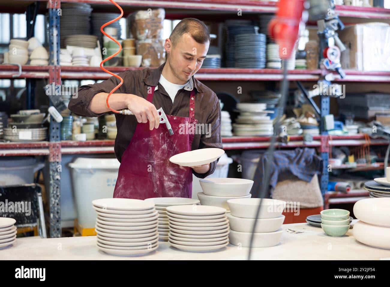 Ceramicist using air blow gun to remove dust from ceramics Stock Photo ...