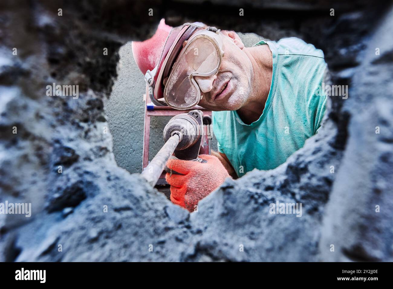 Builder pounding chiseling into tough concrete with rotary hammer Stock ...