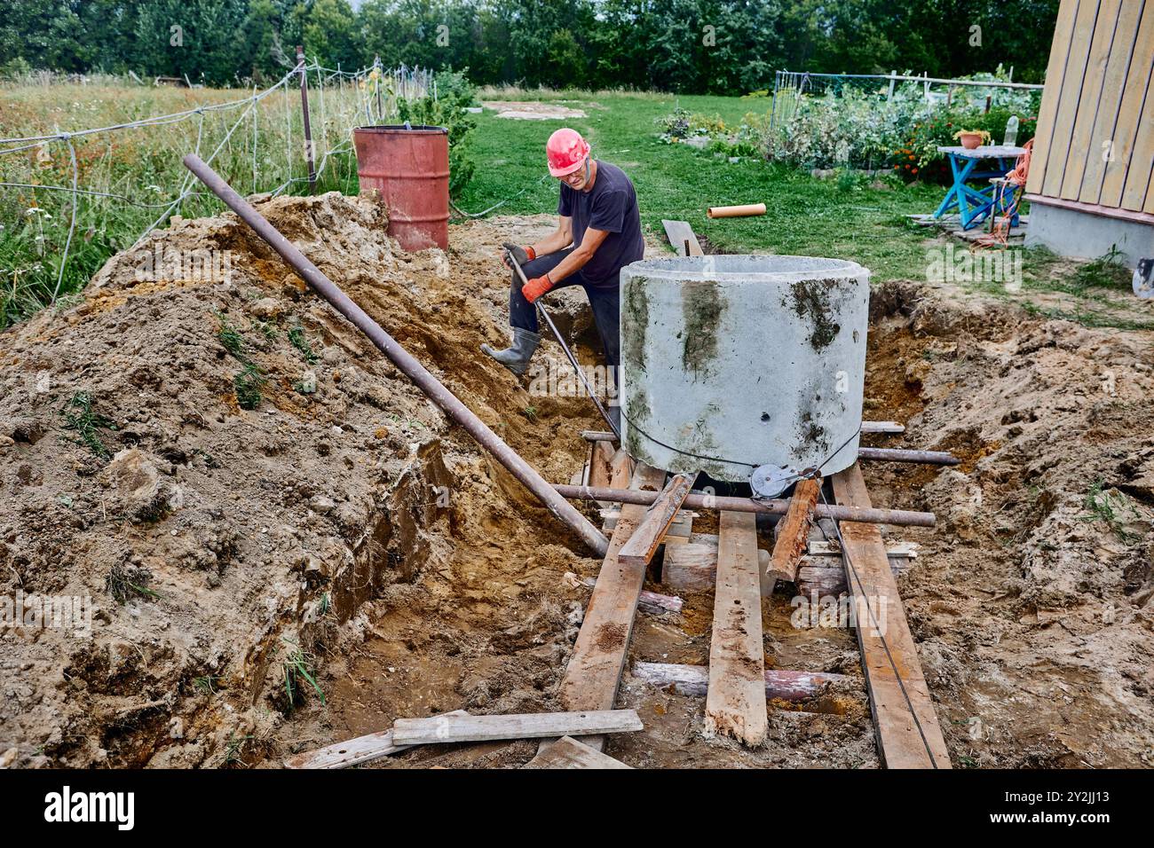 Homeowner uses roller deck to lower one concrete ring on top of another ...