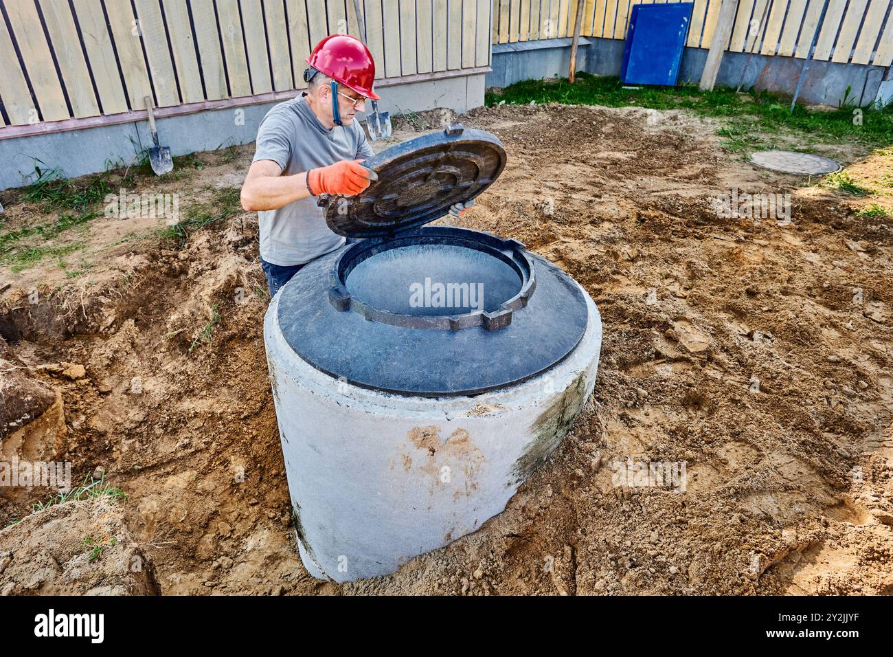Installing manhole cover on septic tank made of concrete rings Stock ...