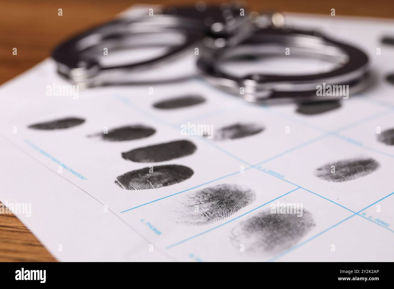 Paper sheet with human fingerprints and handcuffs on table, closeup ...