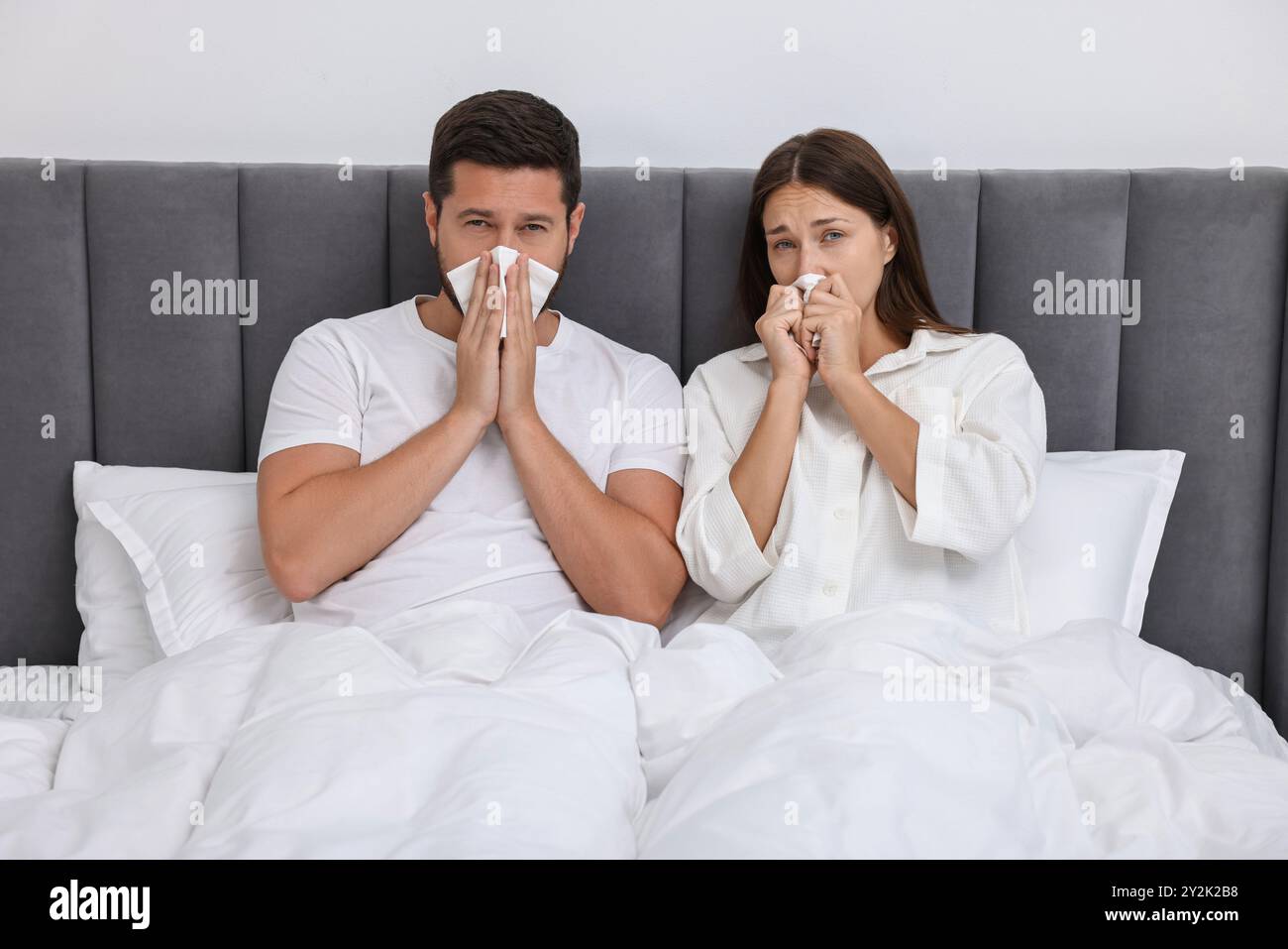 Cold symptom. Couple suffering from fever in bed at home Stock Photo ...