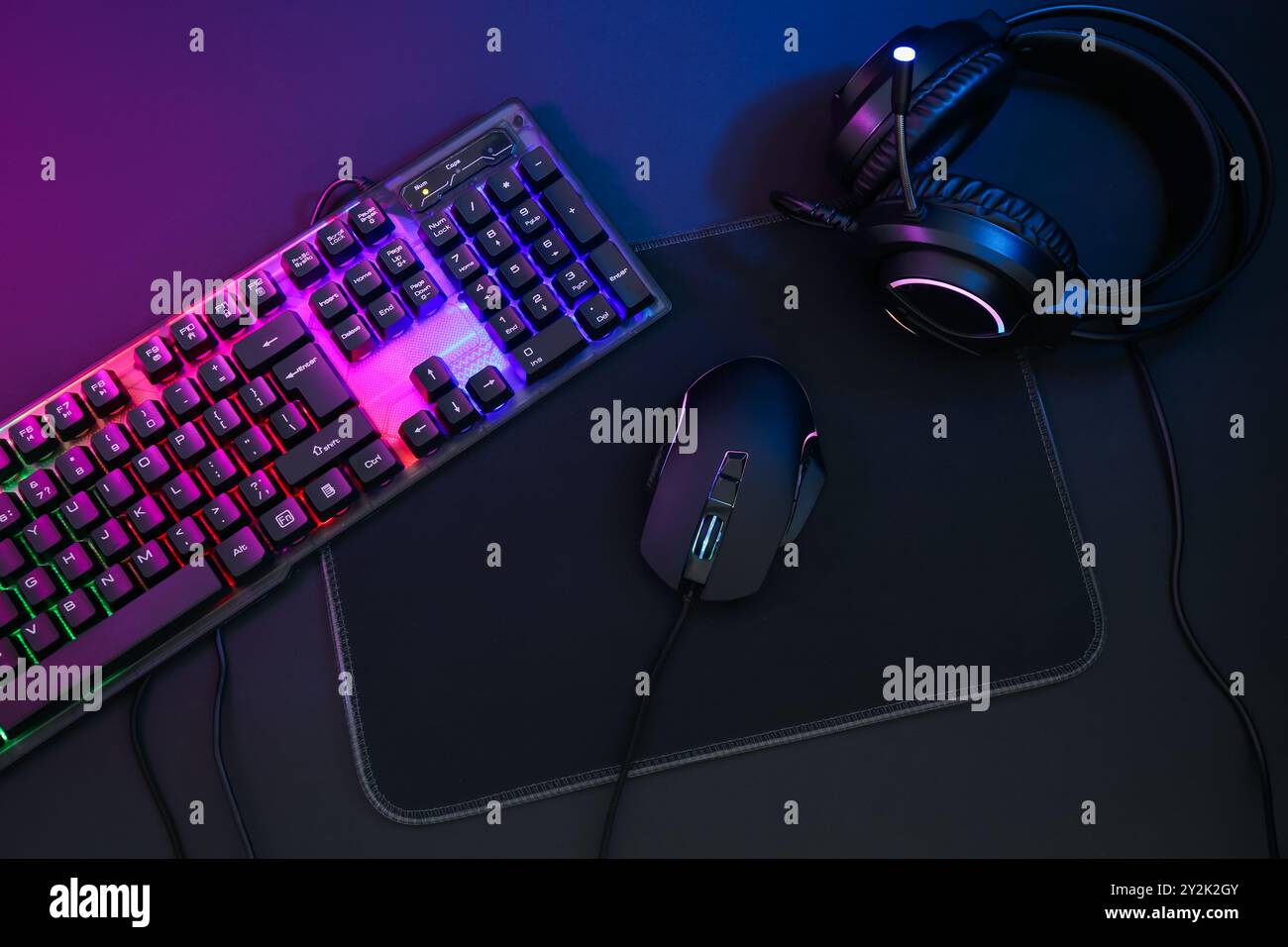 Computer mouse, headset and RGB keyboard in neon lights on dark ...
