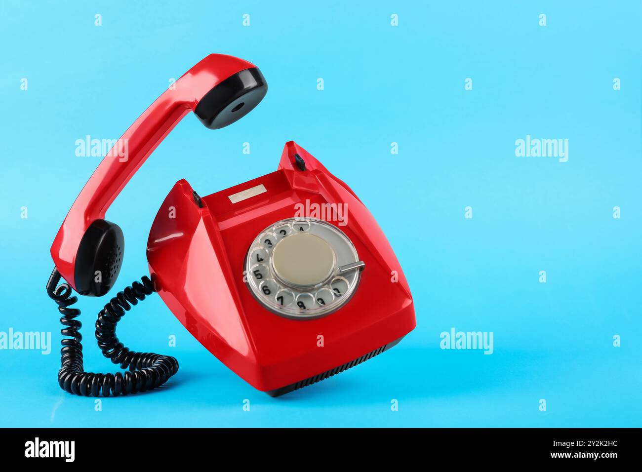 Red telephone with handset on light blue background, space for text ...