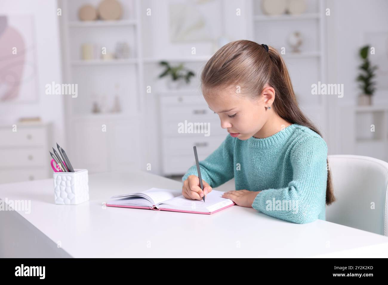 Girl with correct posture doing homework at white desk indoors Stock ...