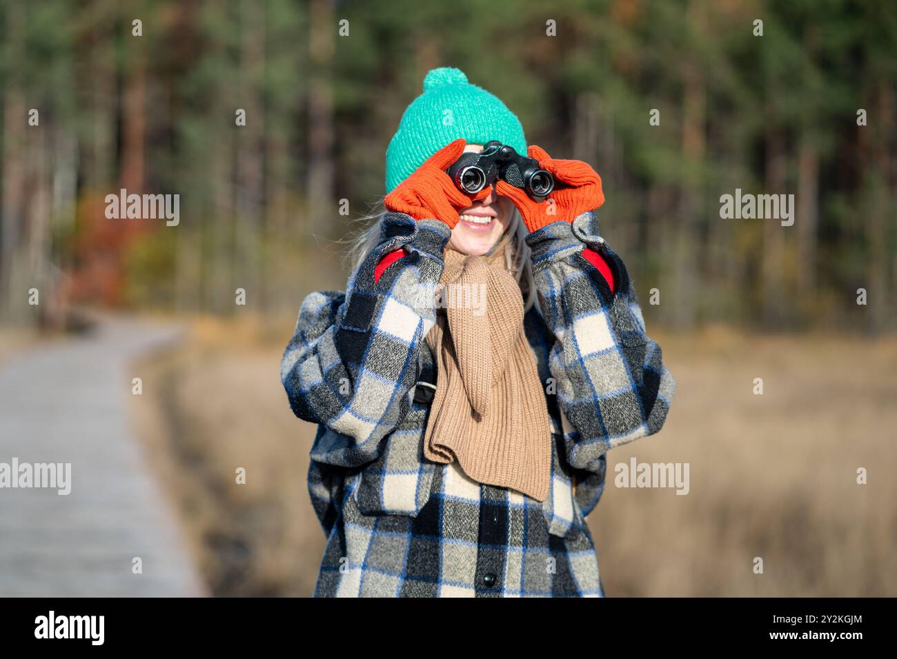 Interested woman bird-watcher smiling looks trough binoculars walks in ...
