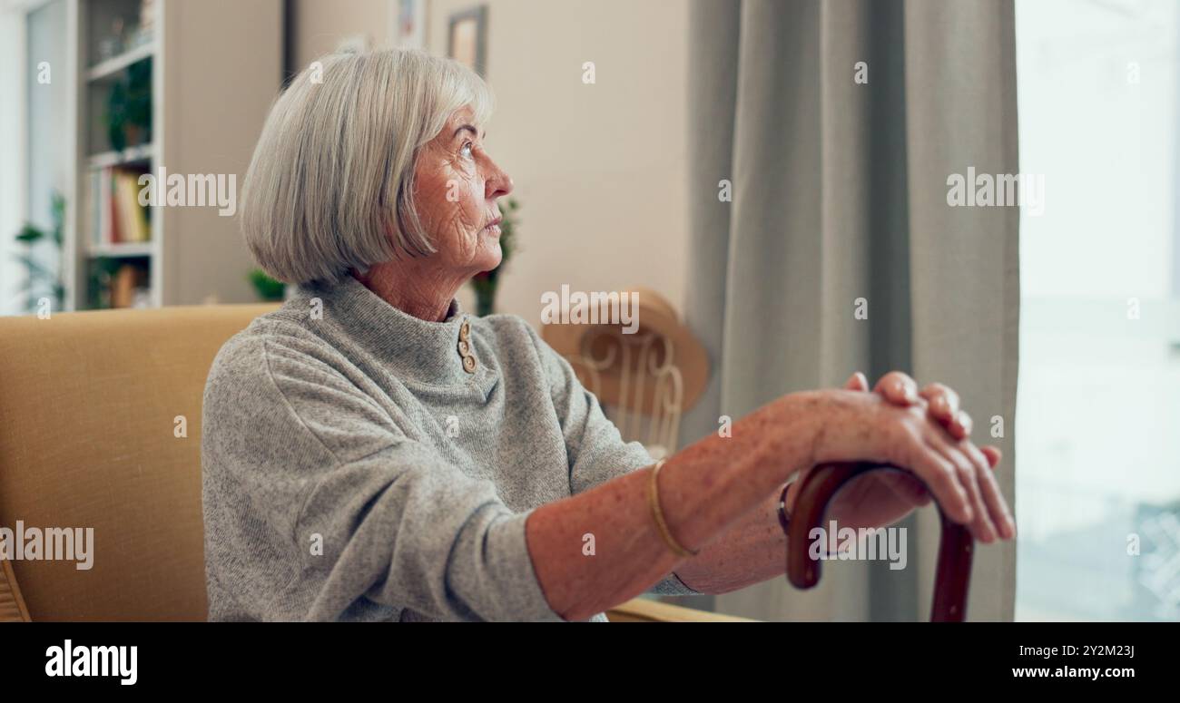 Senior woman, walking stick and sofa with thinking in home for memory, mobility and recovery ...