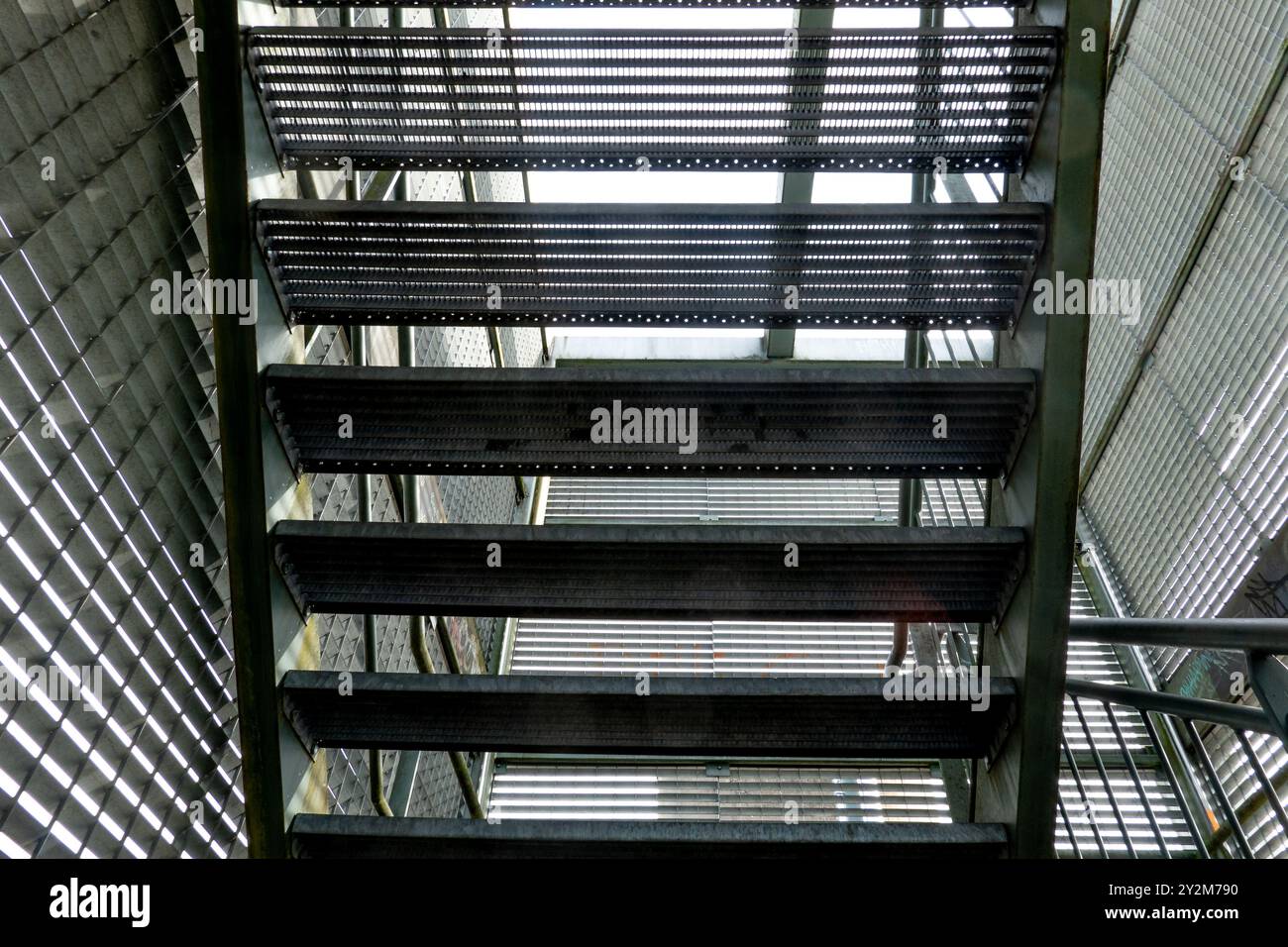 A steel staircase ascends within an industrial space, illuminated by ...