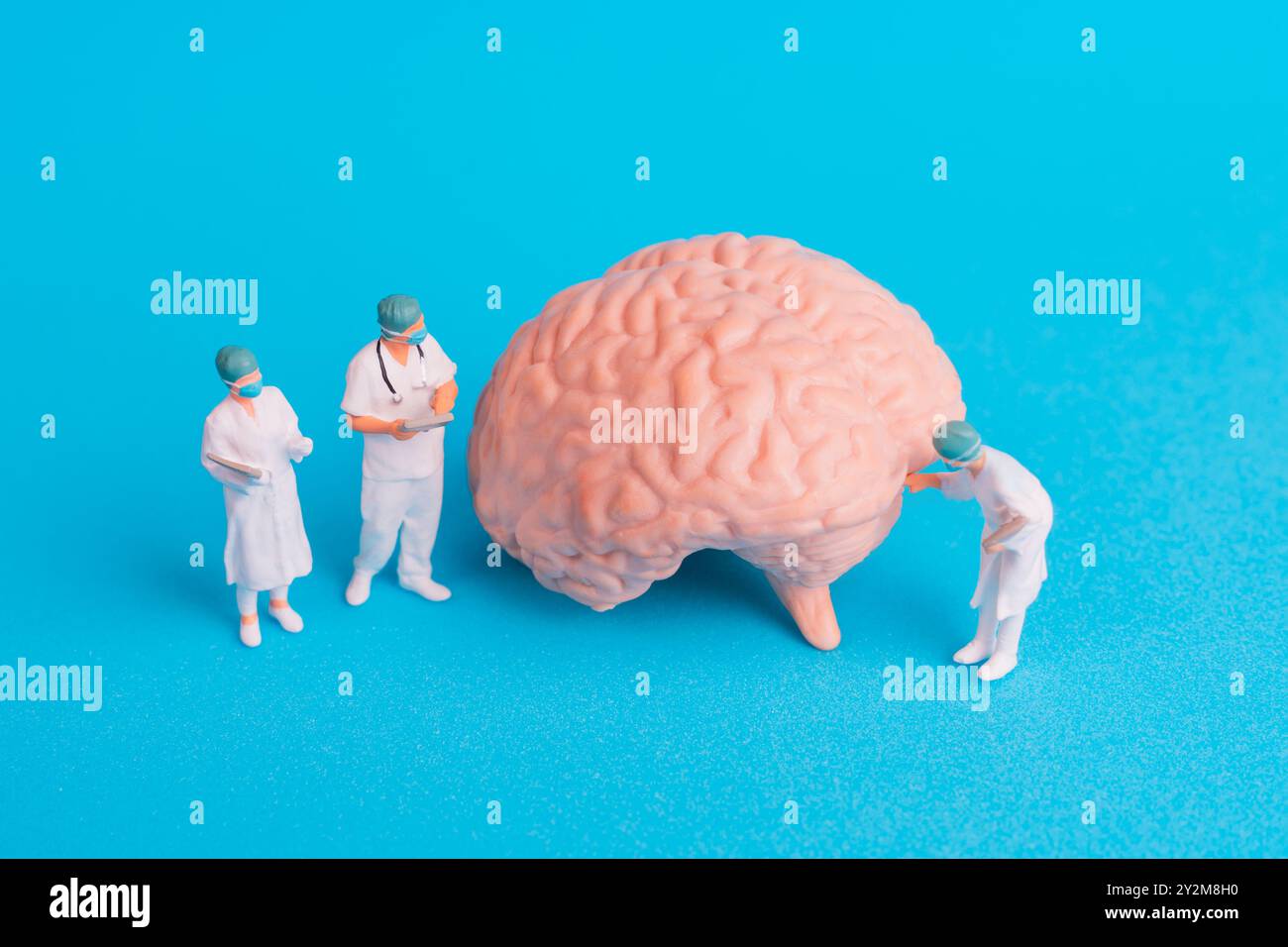 Surgical team figurines inspecting and operating on a realistic brain ...