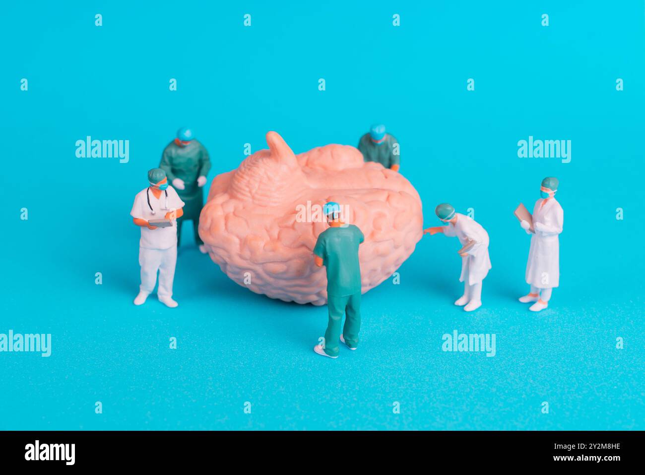 Group of miniature surgeon figurines examining a realistic brain model ...