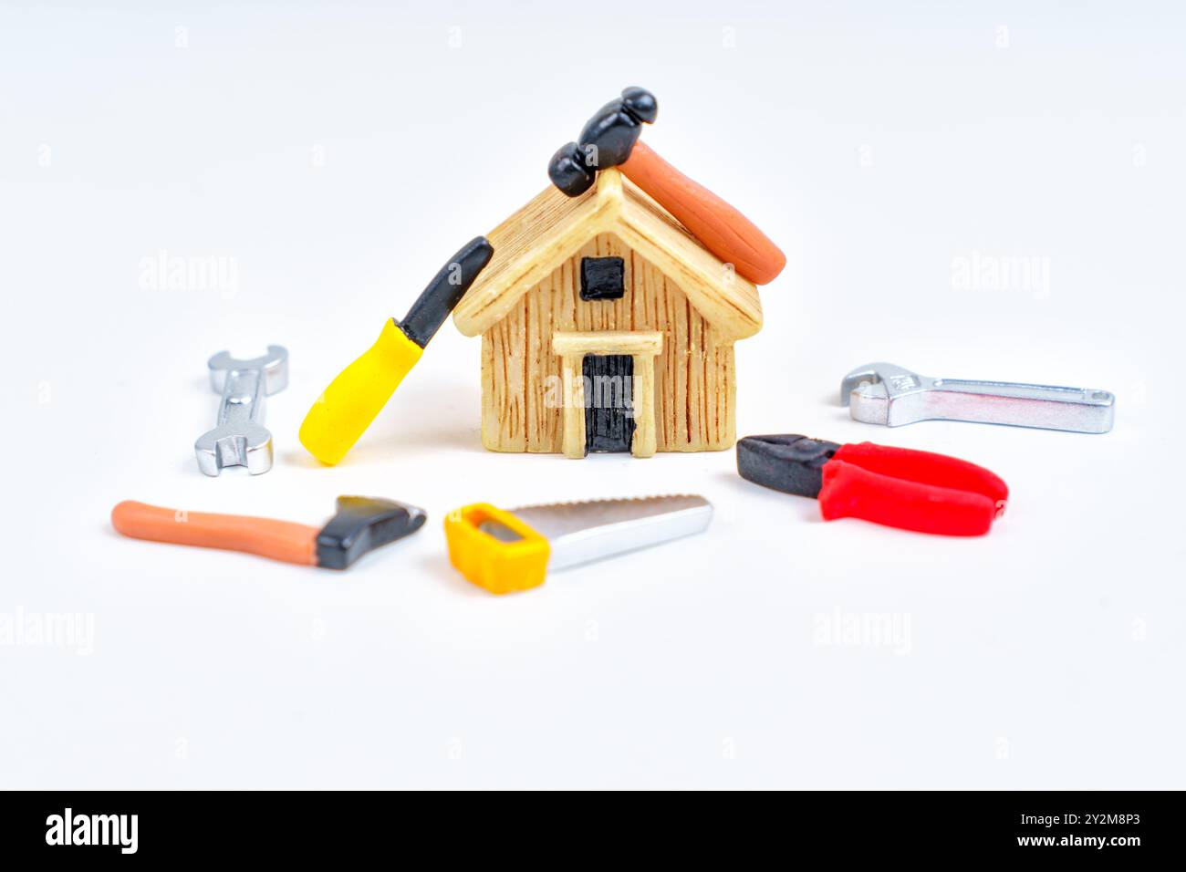Wooden model of house alongside miniature hand tools like hammer ...