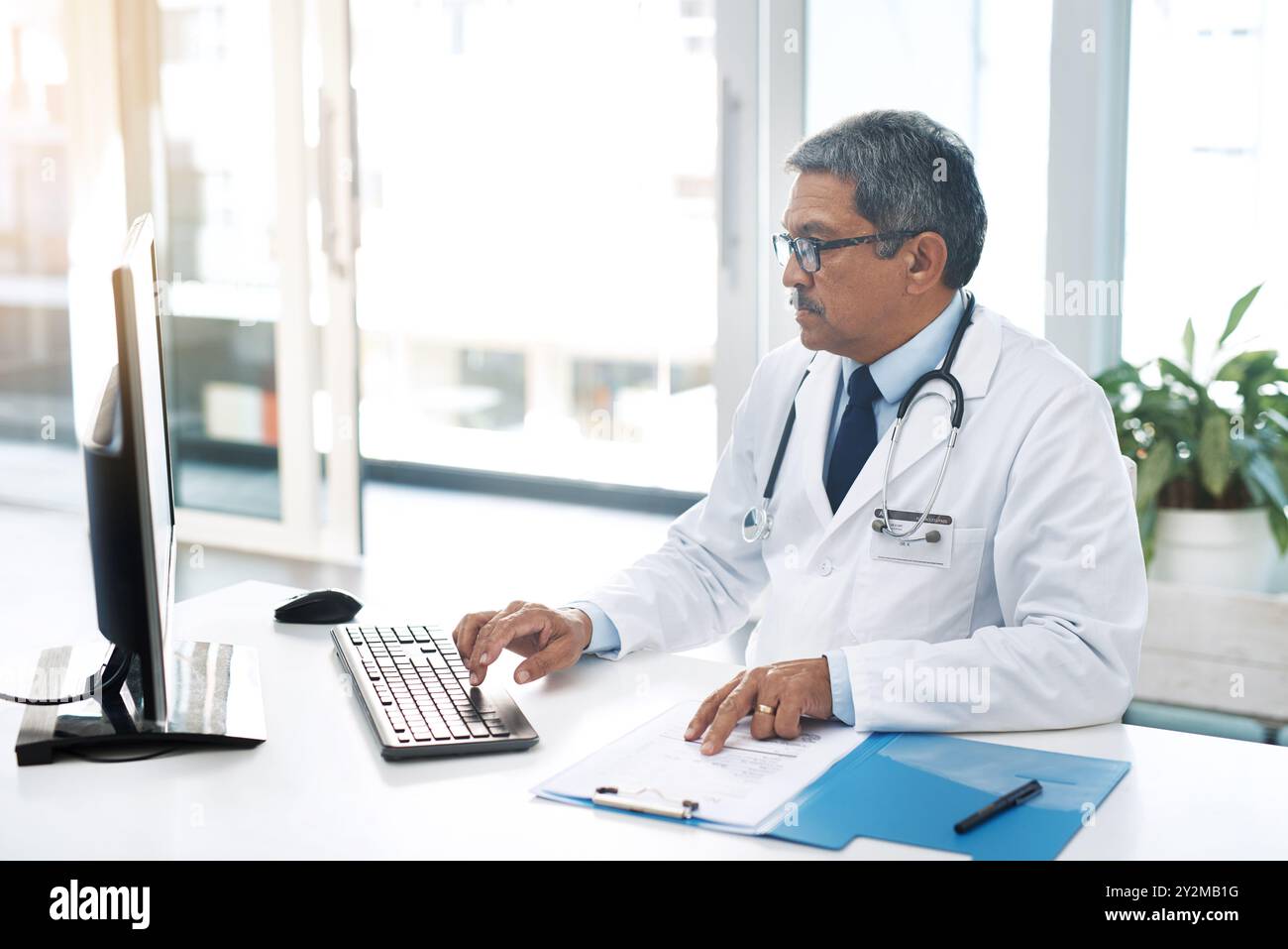 Mature man, doctor and office on computer with file for patient records ...