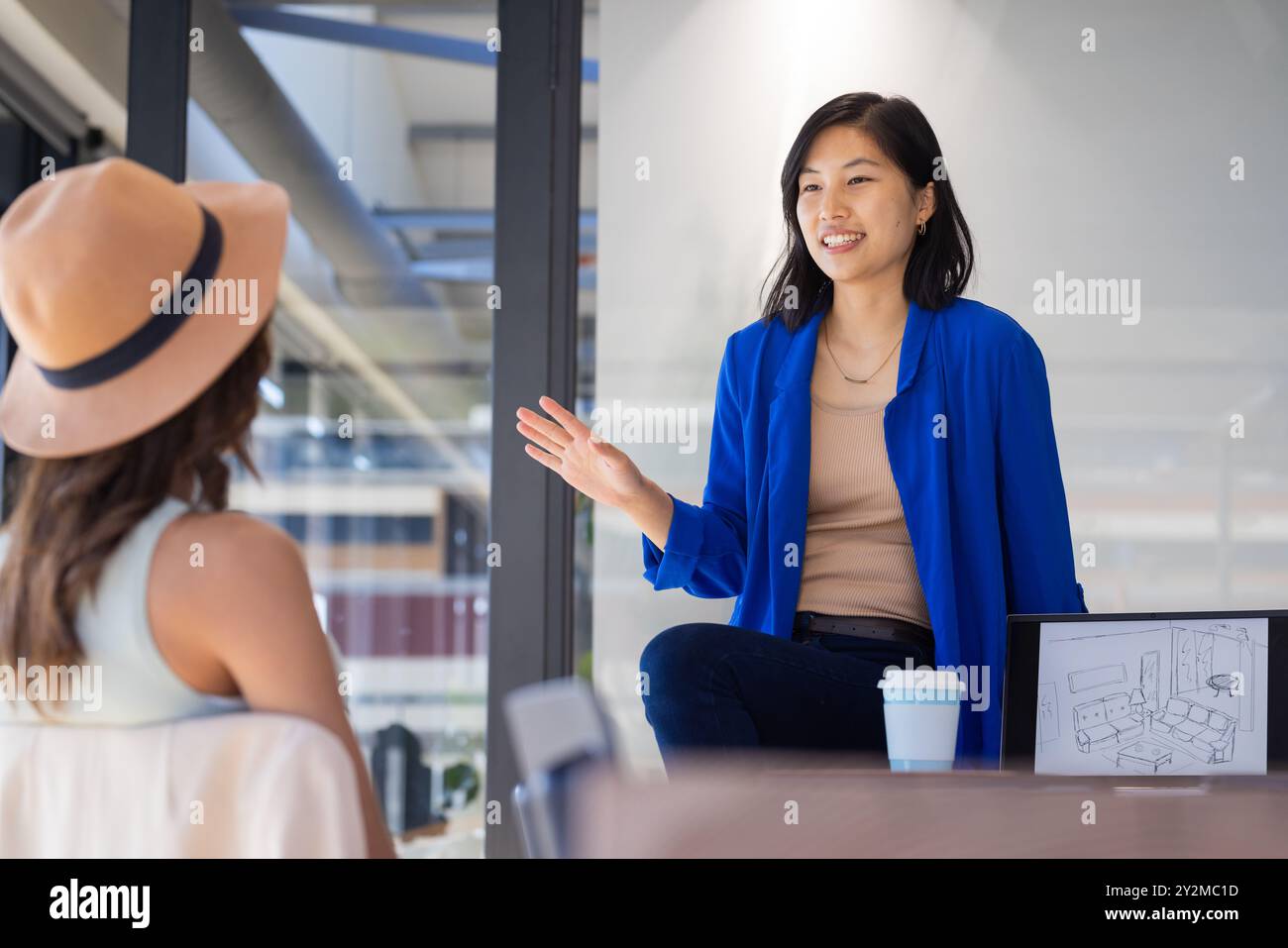 At office, Asian woman discussing project with client, showing room ...
