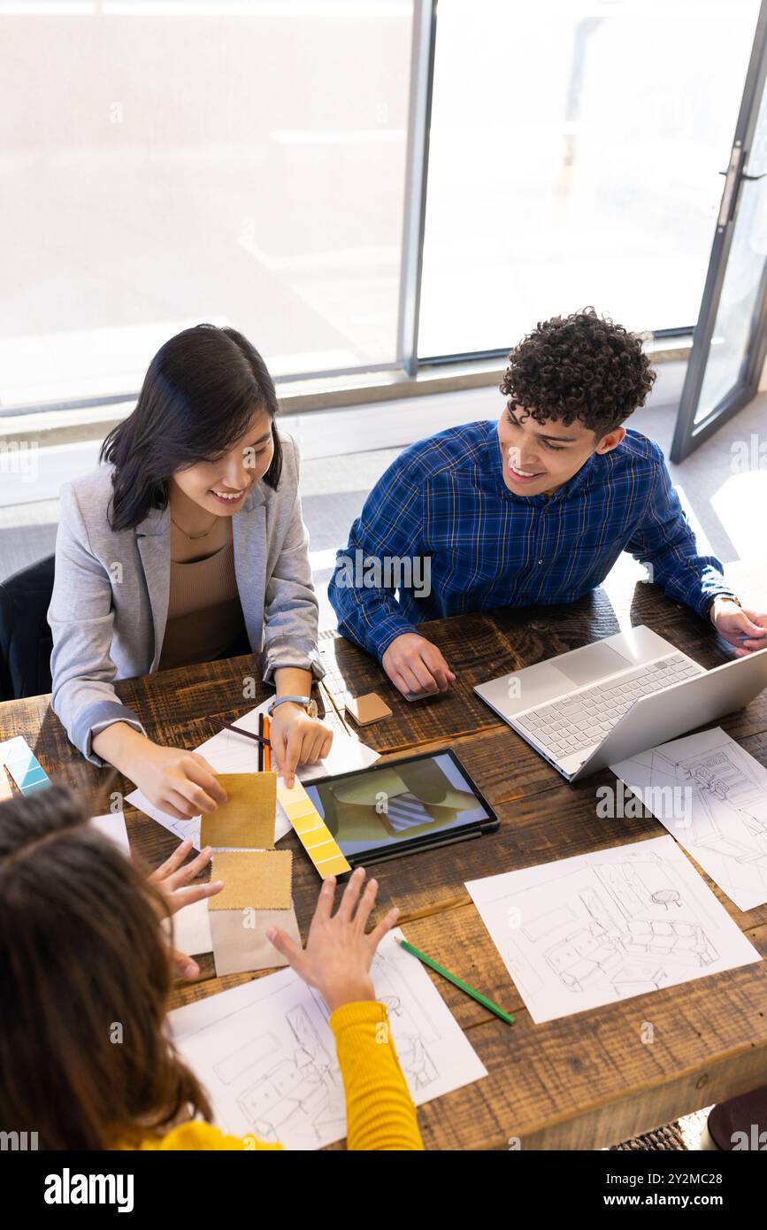 At office, Collaborating on project, diverse team using laptop, tablet ...