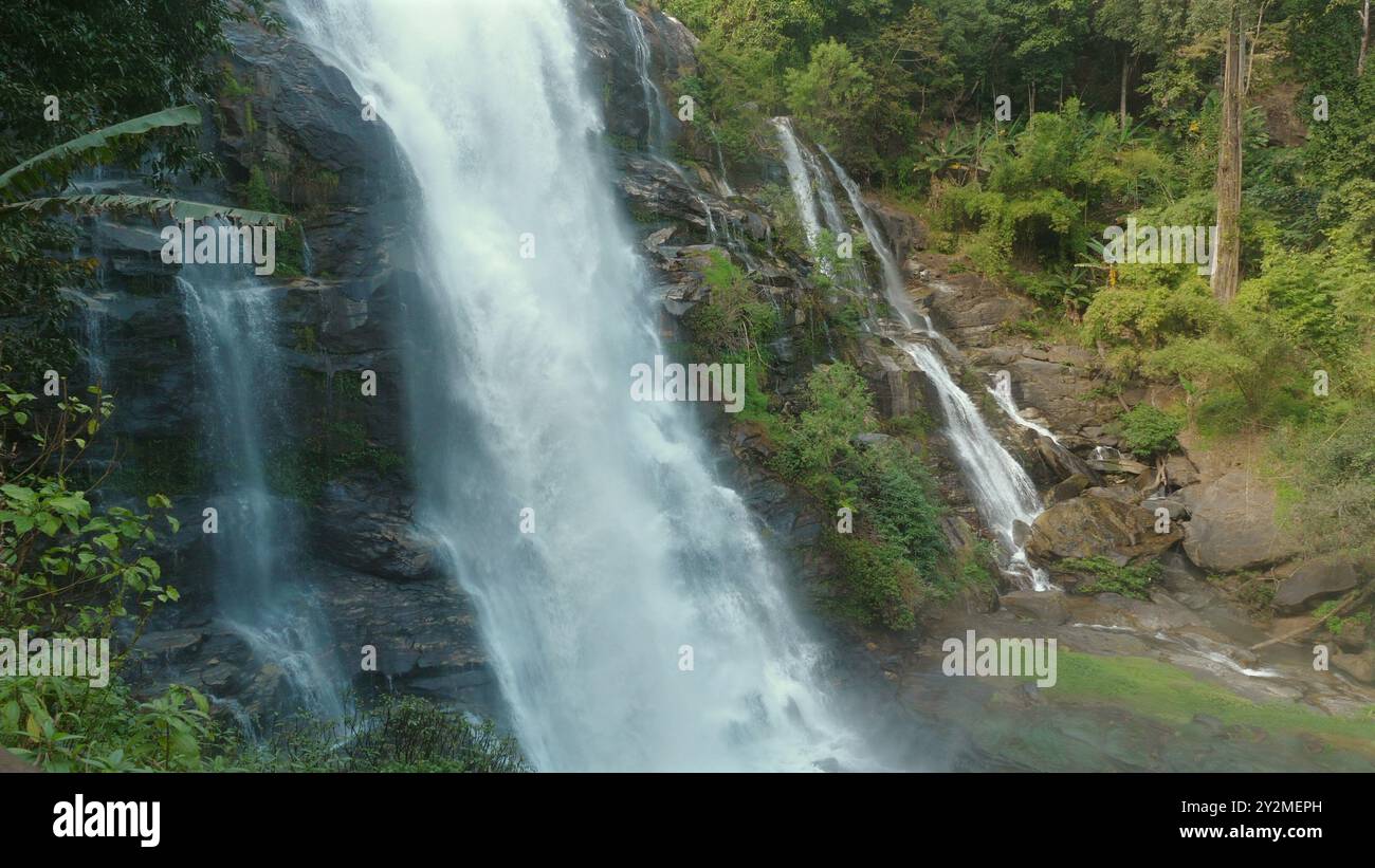 Majestic waterfall cascading over rugged cliffs into lush forest below ...