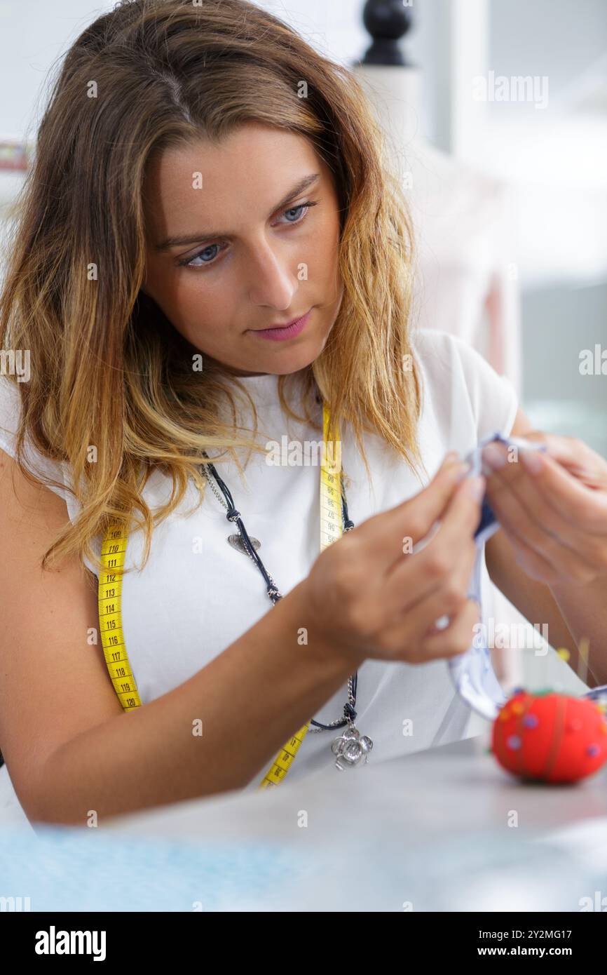 female tailor inserting thread in needle Stock Photo - Alamy