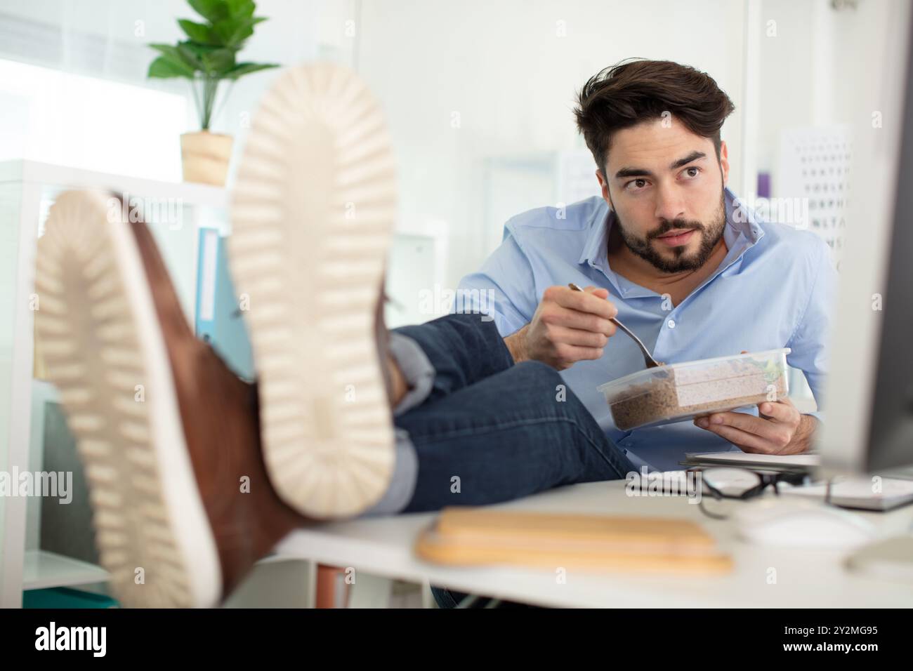 young man eating lunch while working Stock Photo - Alamy