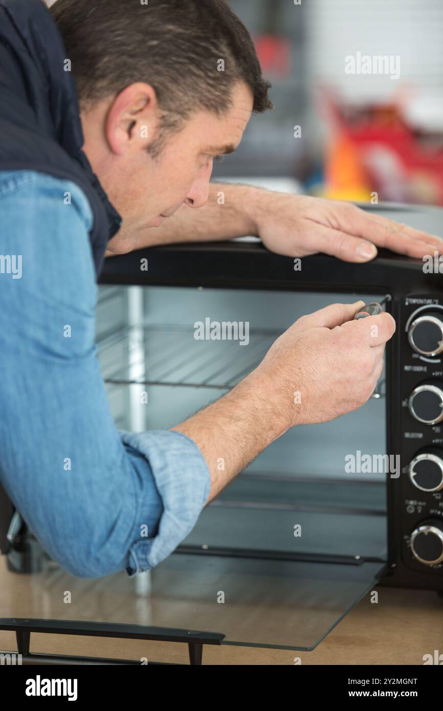 a male worker fixing an oven Stock Photo - Alamy