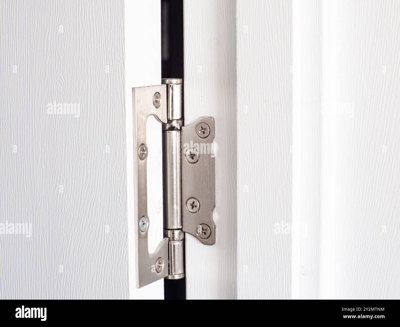 Close-up of a worn-out door hinge with steel attachments on door jamb ...