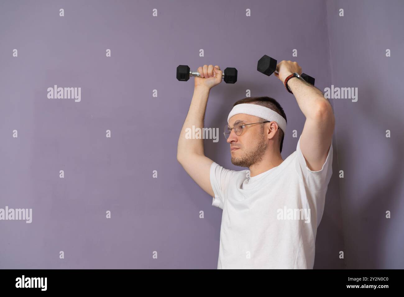A determined man lifts a dumbbell in a home gym, showcasing strength ...