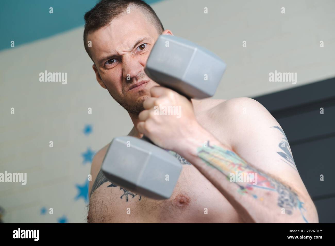 A determined man lifts a dumbbell in a home gym, showcasing strength ...