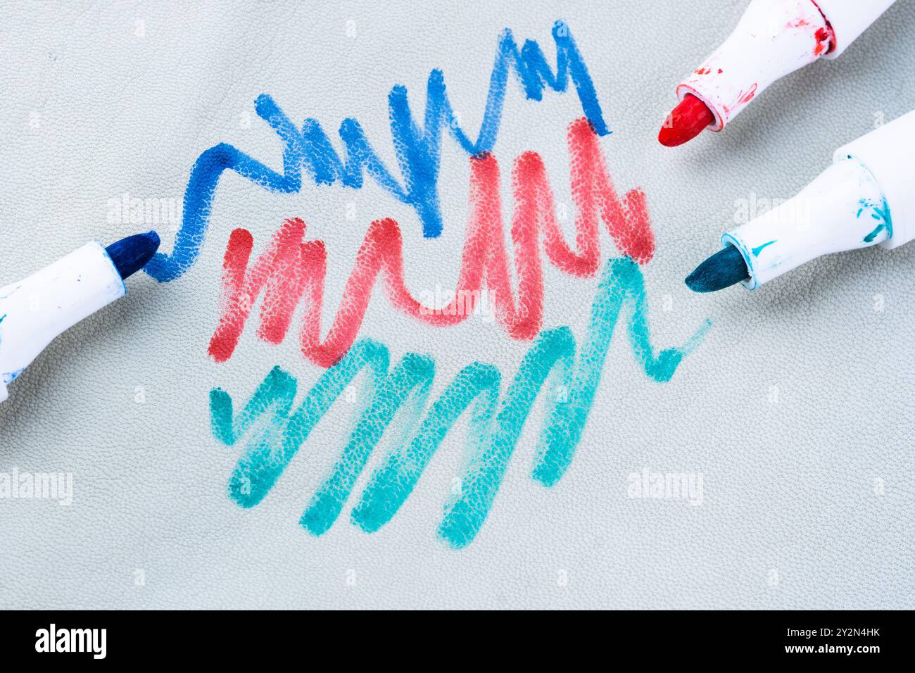 A child's hand drawing felt-tip pens on the white upholstered furniture ...