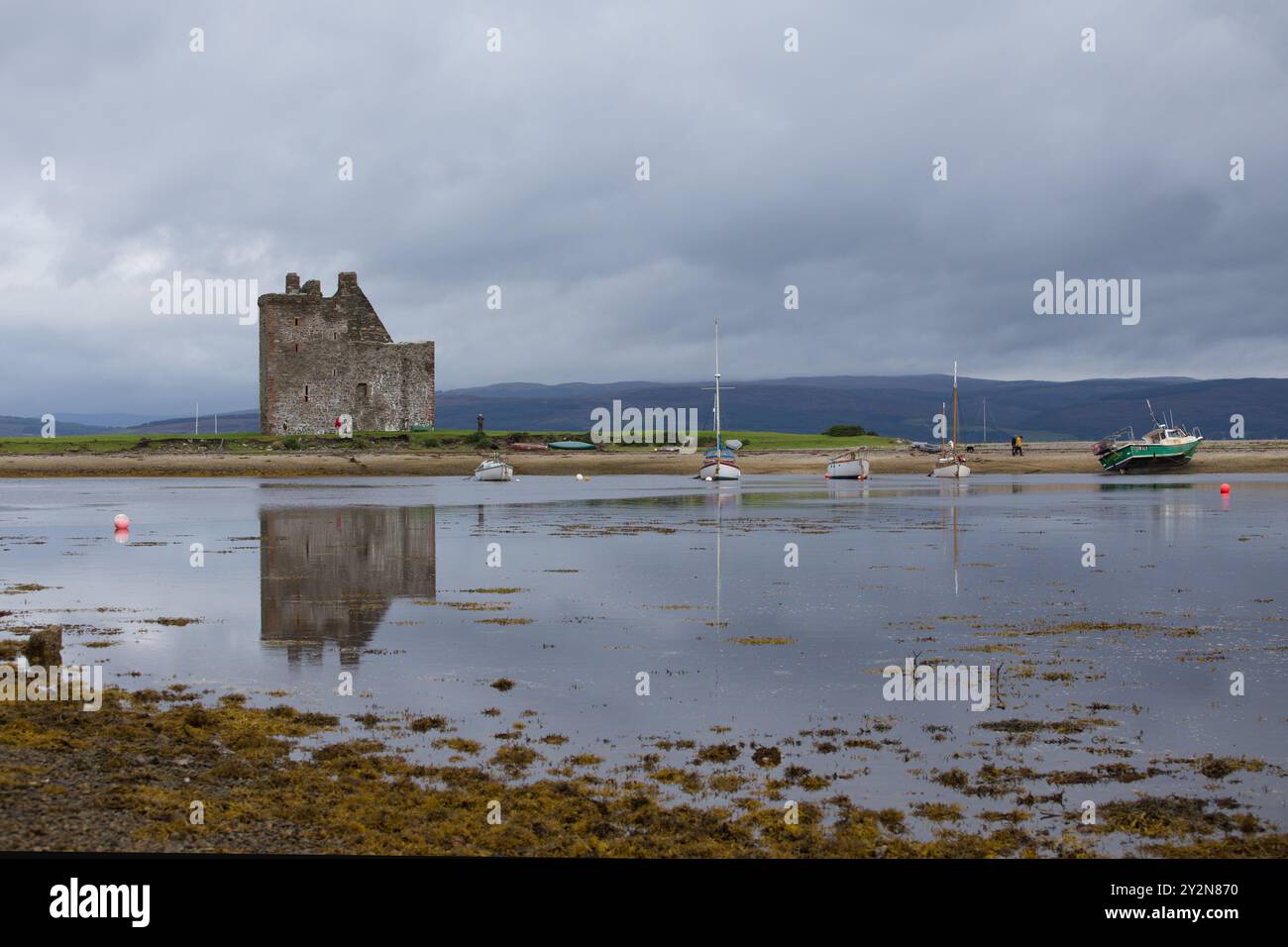Lochranza Castle reflected in the still waters of Lochranza Harbour at ...