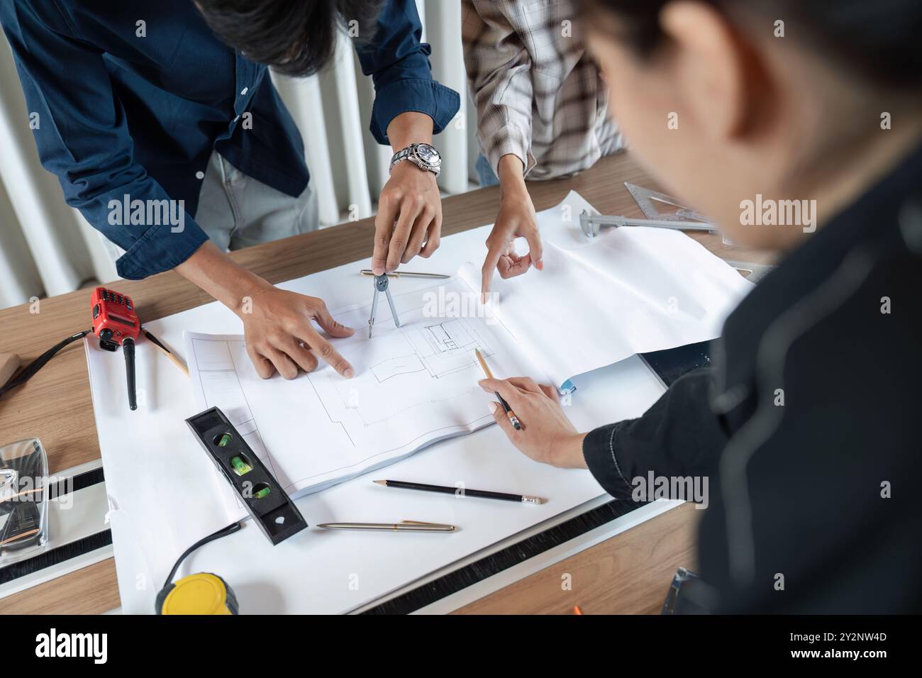 Collaborative Team of Architects Discussing Blueprints and Design Plans ...