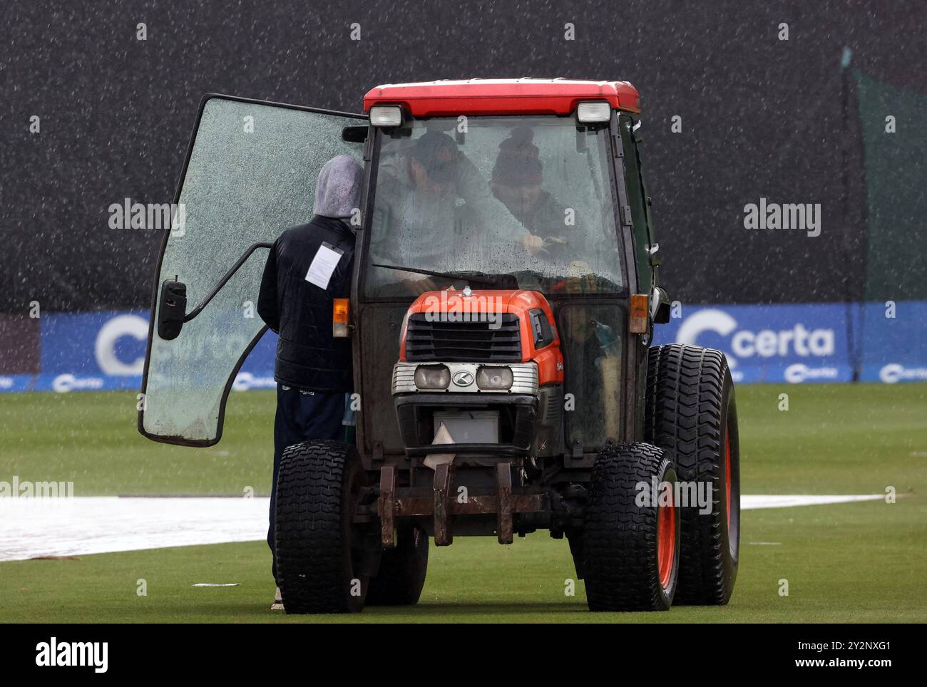 Ground staff take shelter in a small tractor as rain delays play ahead ...