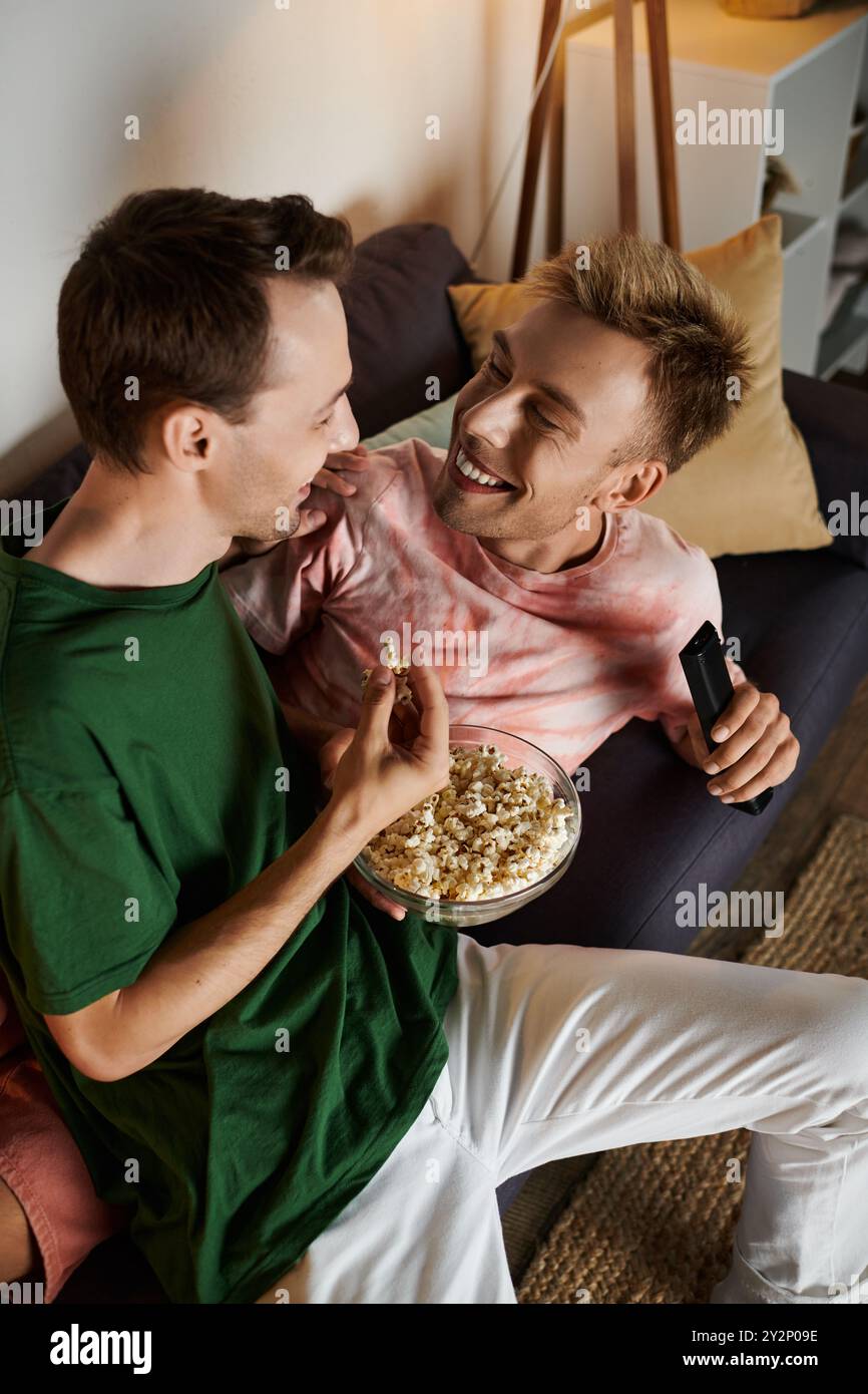 Two men share a joyful moment while cuddling on the couch Stock Photo ...