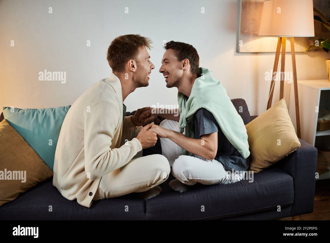 Two men share a joyful moment while cuddling on their cozy sofa Stock ...