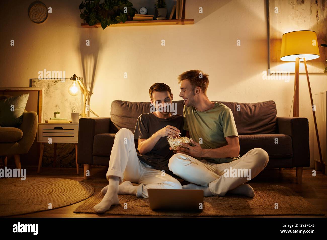 A loving couple shares popcorn while laughing on a cozy evening Stock ...