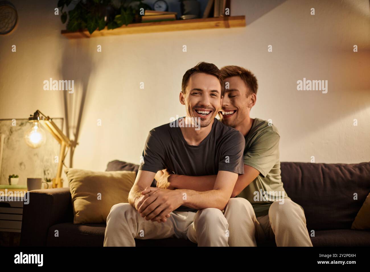 Two men embrace and laugh together in their warm, inviting living room ...