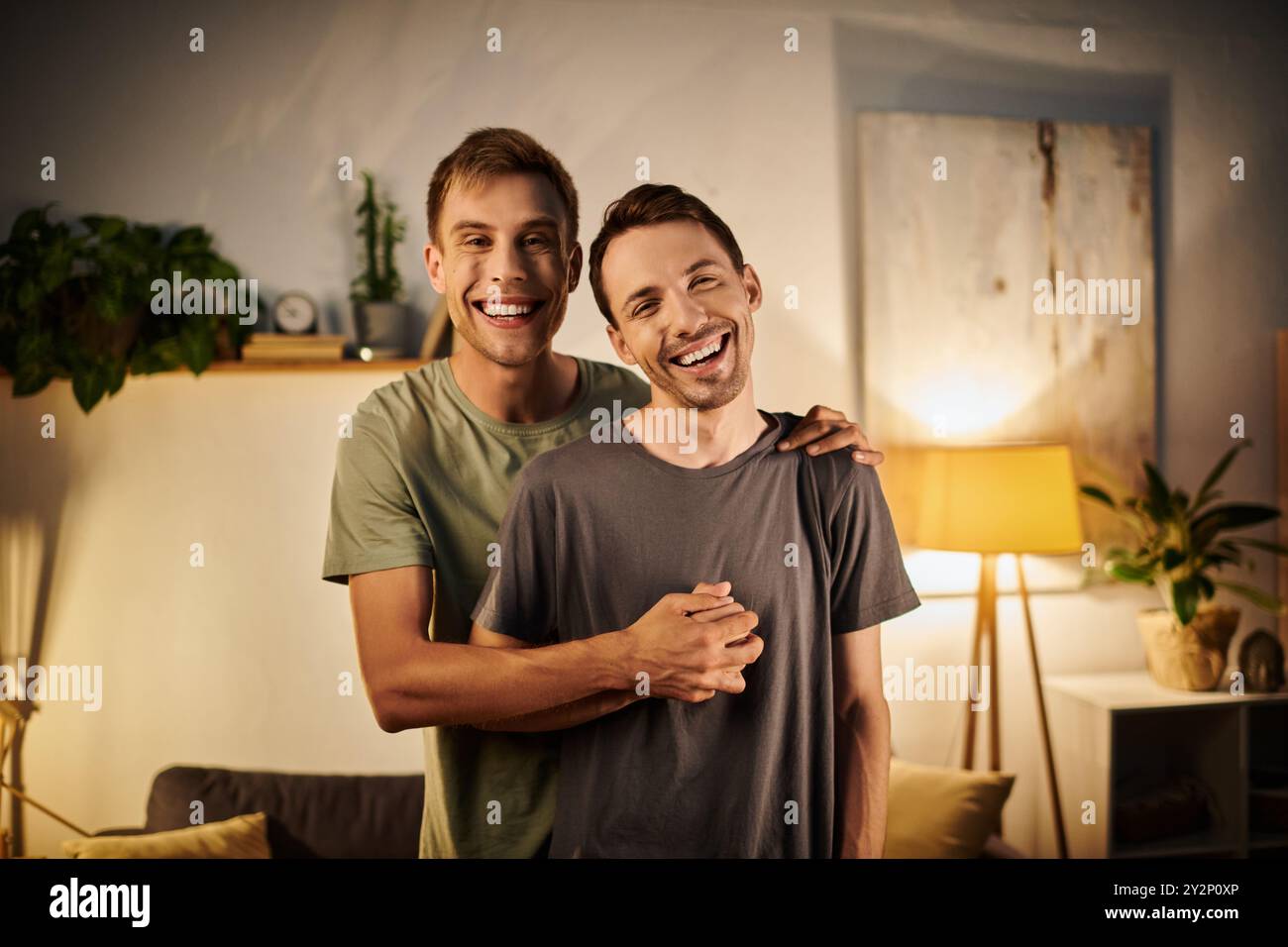 Two men share laughter and warmth in their cozy living room Stock Photo ...