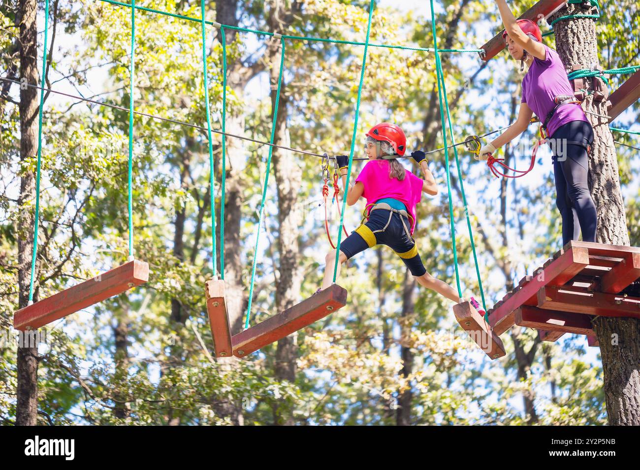 A child with her mother goes through an obstacle course on ropes in a ...
