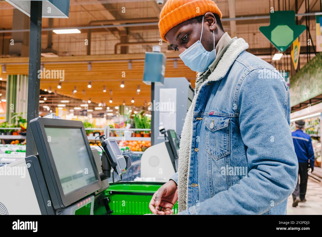 African-American man wearing medical mask and denim jacket uses self ...