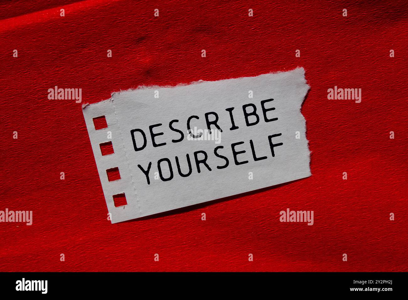 Describe yourself message written on ripped torn paper piece on red background. Conceptual ...