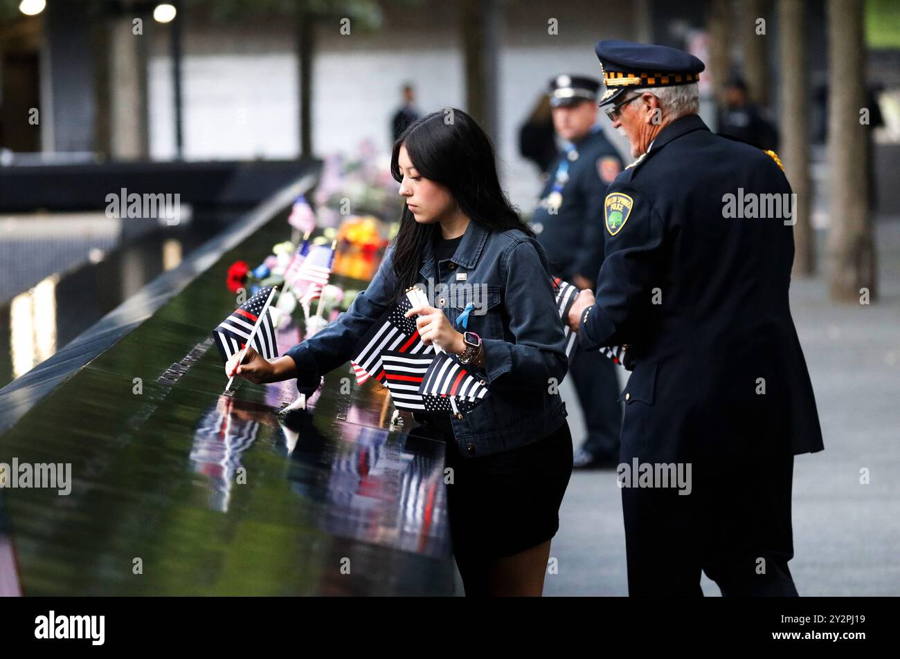 New York, United States. 11th Sep, 2024. A woman places flags on the ...