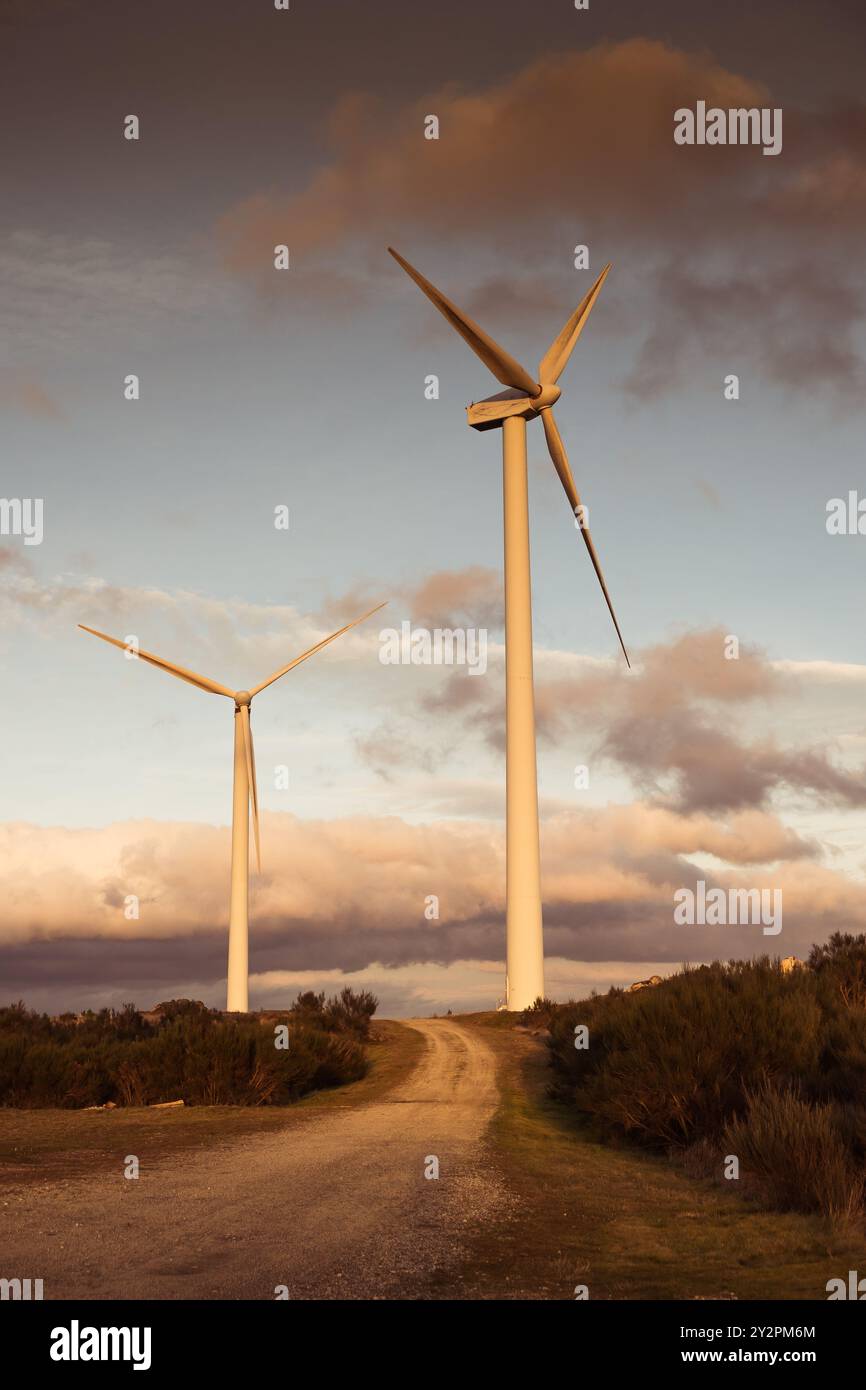 two windmills turbines on a mountain at sunset, golden hour. Concept of ...