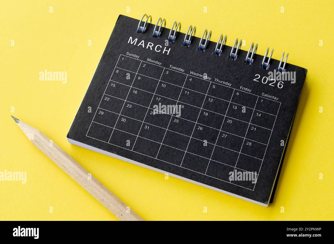 Top view of March 2026 calendar on black notepad with yellow background ...