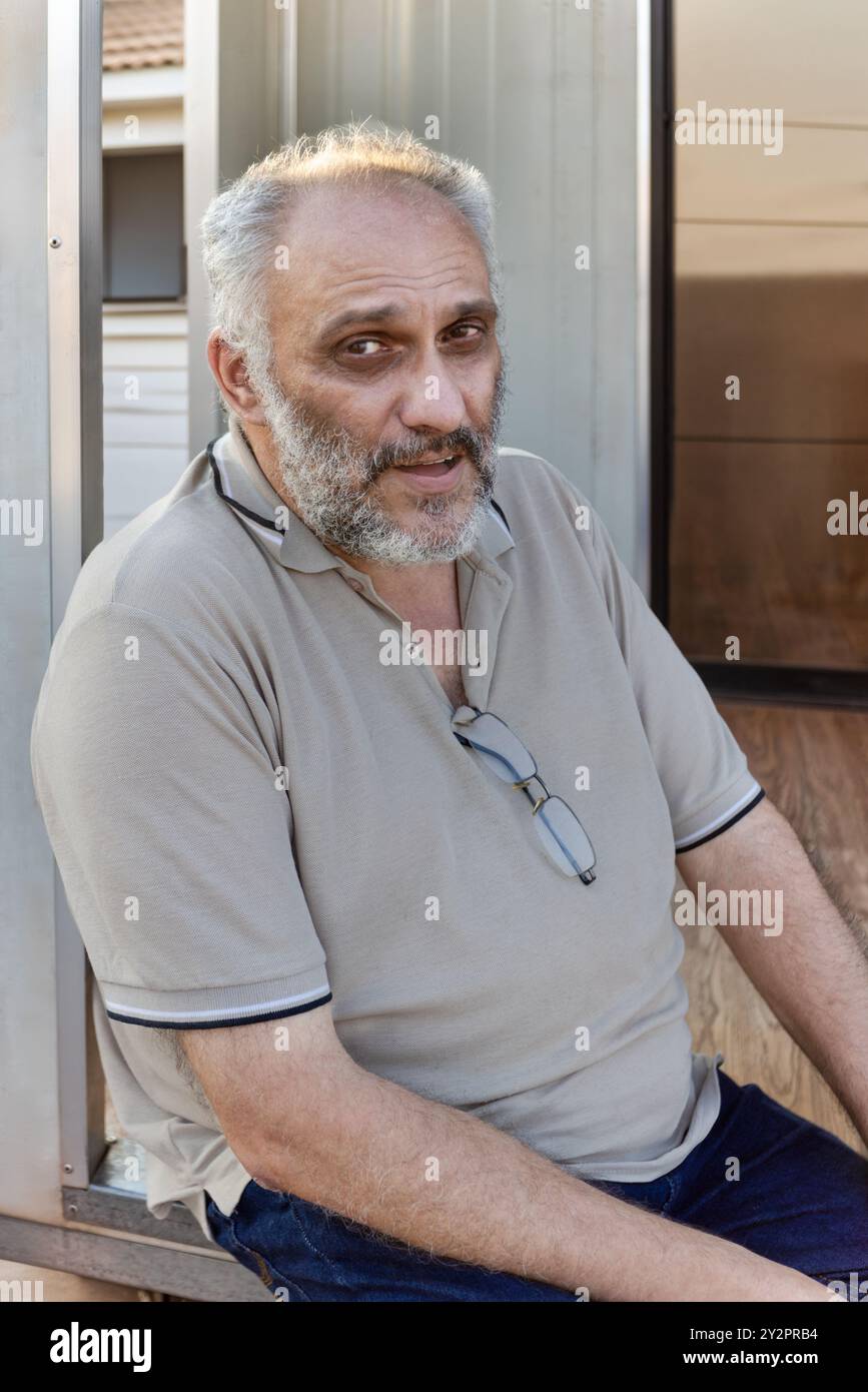 single old man with a beard and gray hair sitting outdoors , half ...