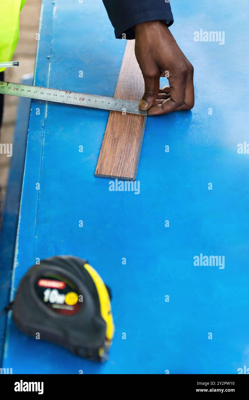 african american worker with a ruler and tape measure measuring wood on ...