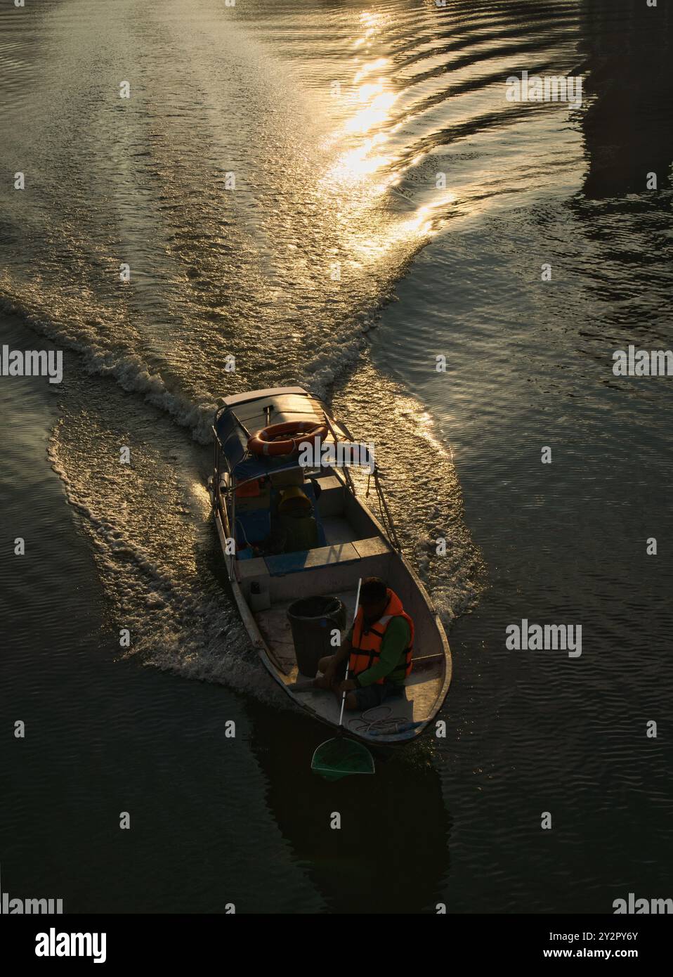 Motor boat moving on water creating ripples and waves during golden ...