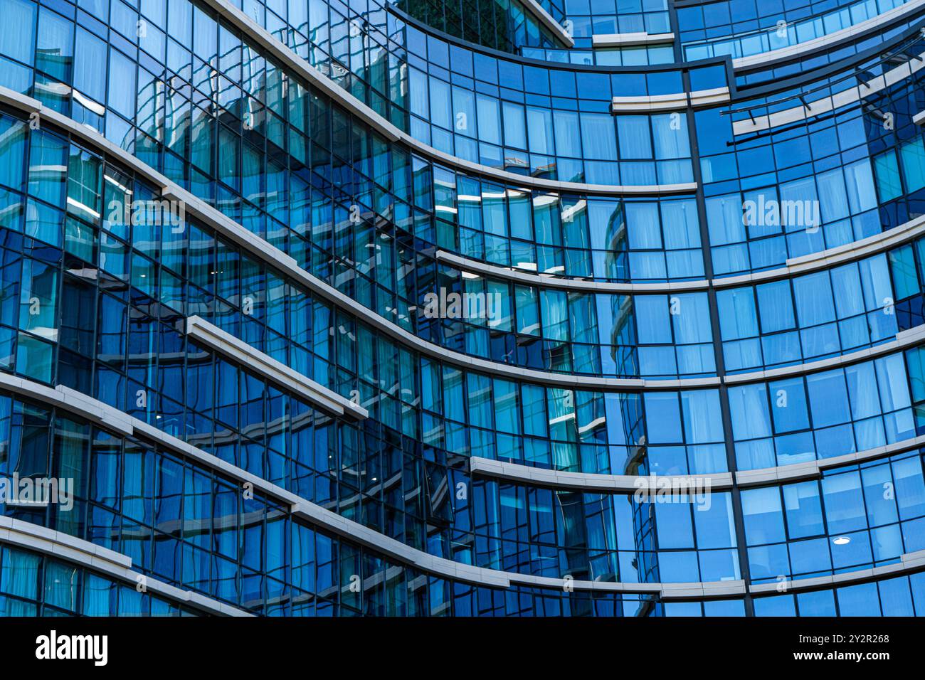 Intricate details of a modern architecture with a curved design, showcasing layered glass panels ...