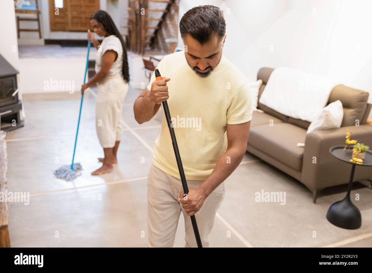 An interracial couple engaging in house cleaning; a black woman and an ...