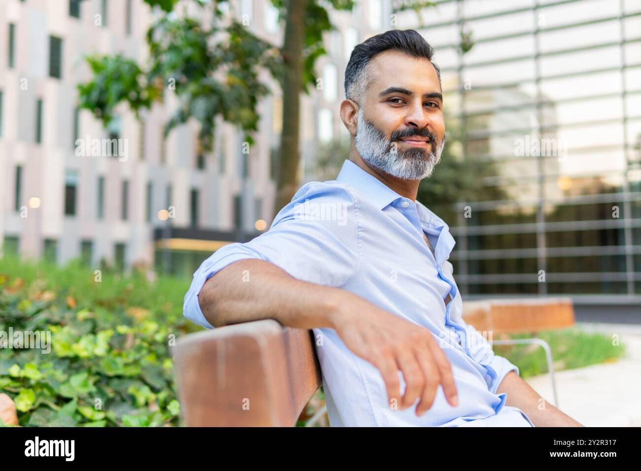 Indian man in formal attire with a gentle smile, sitting casually ...