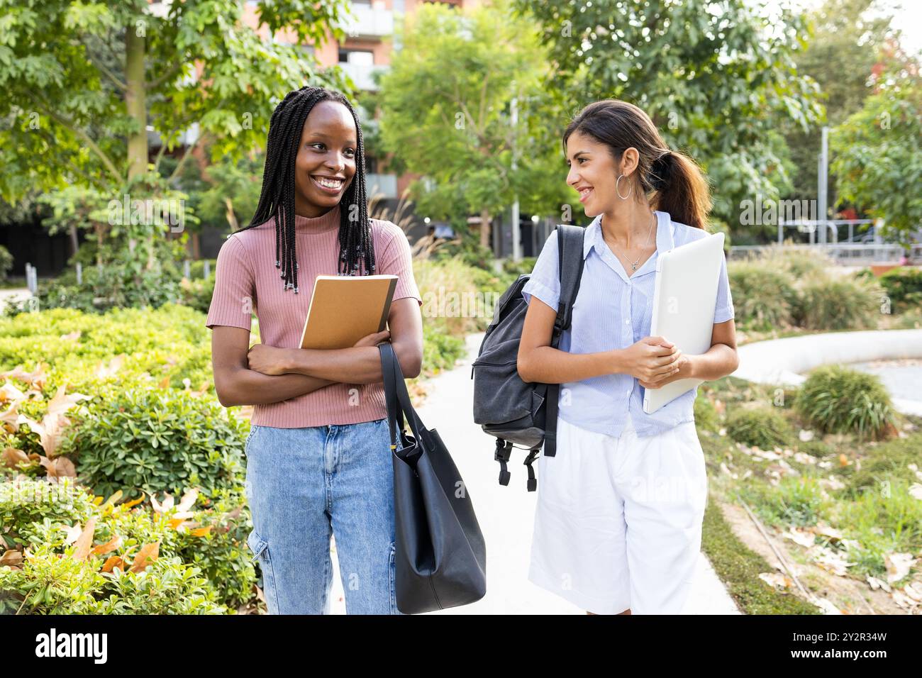 Two multiethnic university students walk and converse cheerfully on a ...
