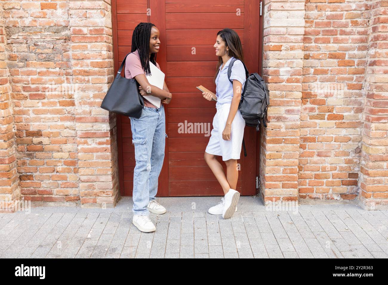 Two young multiethnic students, one with braided hair and the other ...